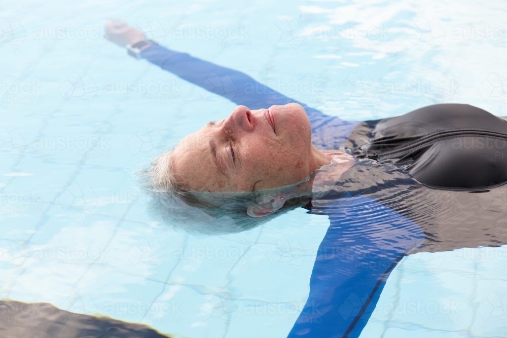Image of Relaxed active senior lady floating in swimming pool ...