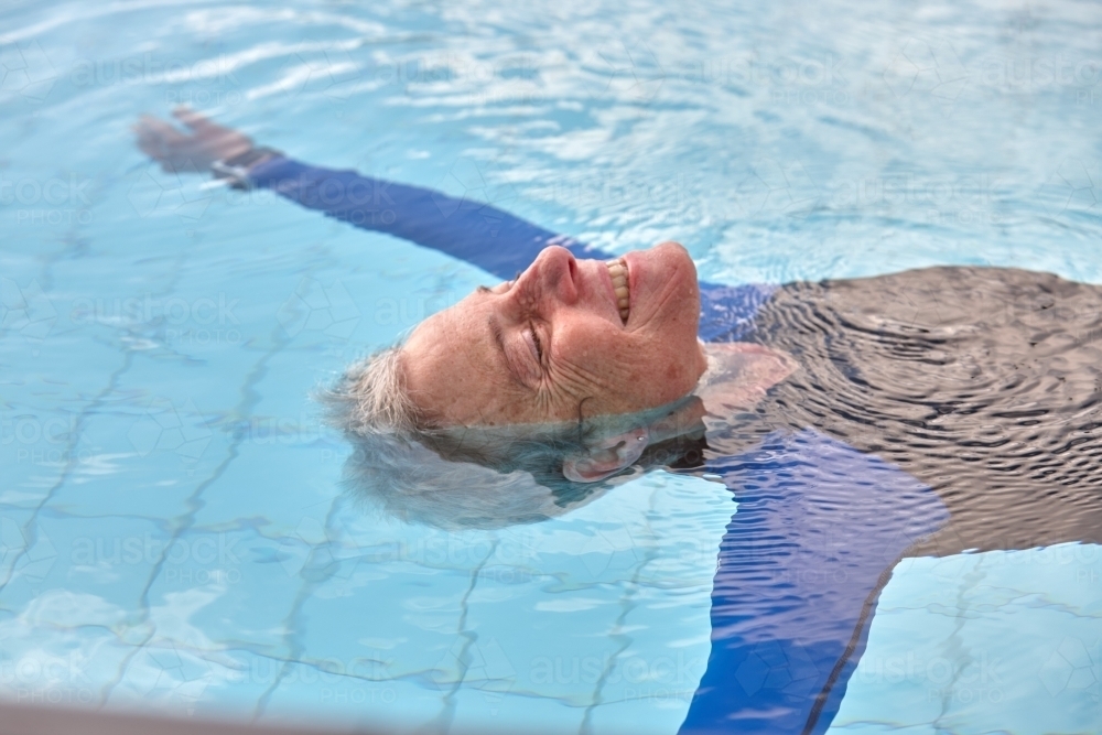 Image of Relaxed active senior lady floating in swimming pool ...