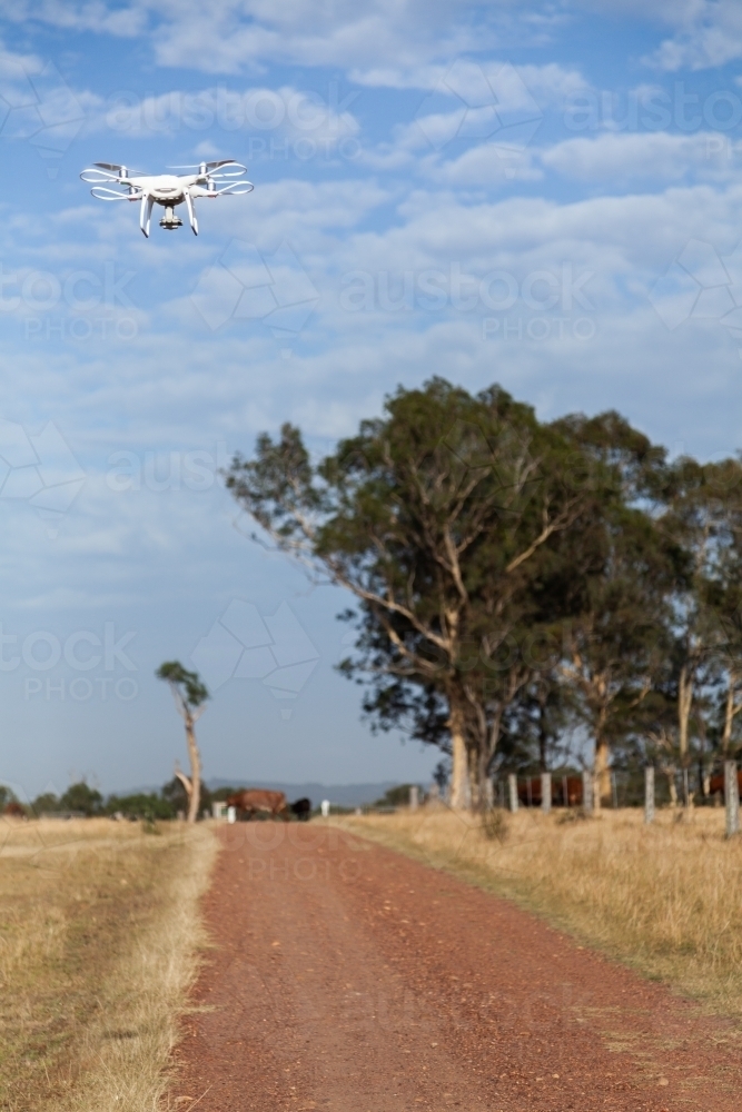 Image of Remotely piloted aircraft flying over farm driveway - Austockphoto