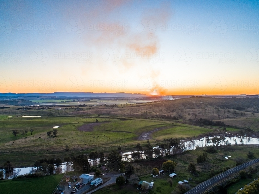 Image of river and farmland with bushfire smoke on horizon at sunset ...
