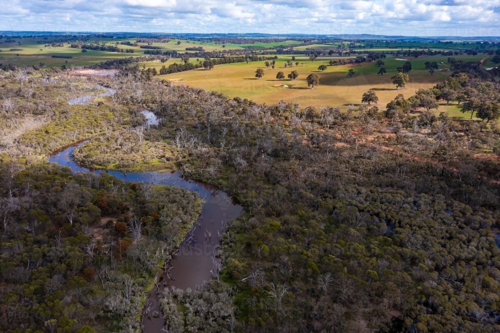 Image of river winding through bush reserve near farmland - Austockphoto