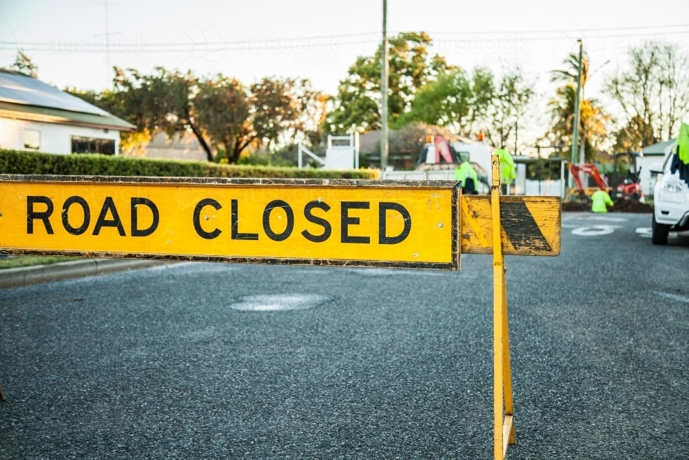 Image of Road closed sign with trucks and digger behind - Austockphoto