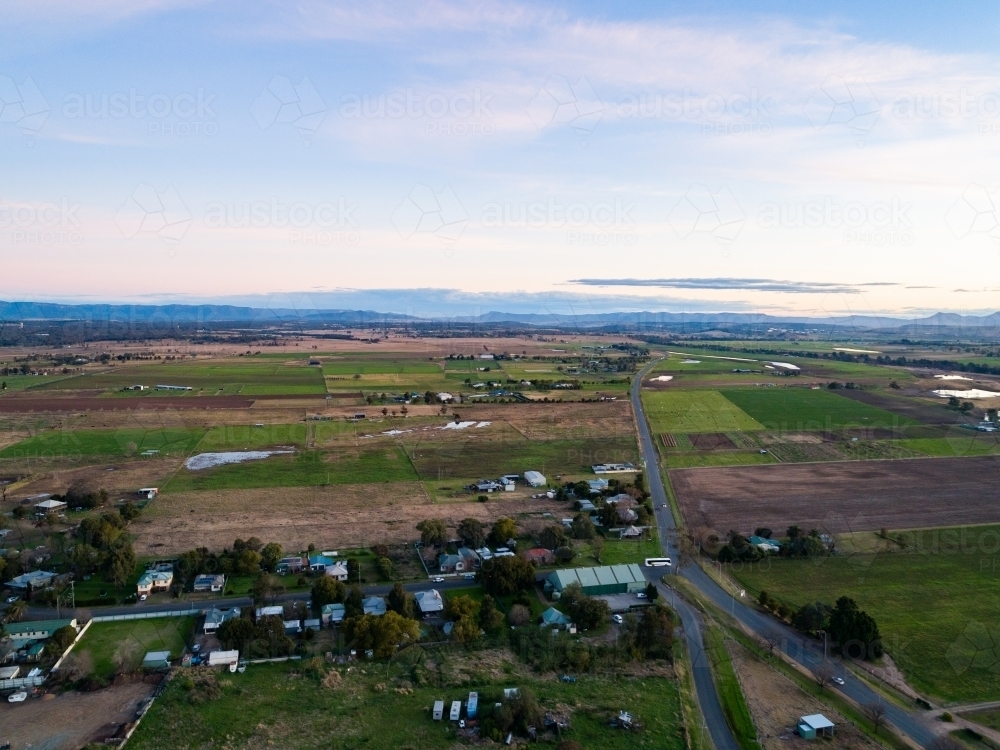 Image of road leading out of town through farm paddocks at dusk ...