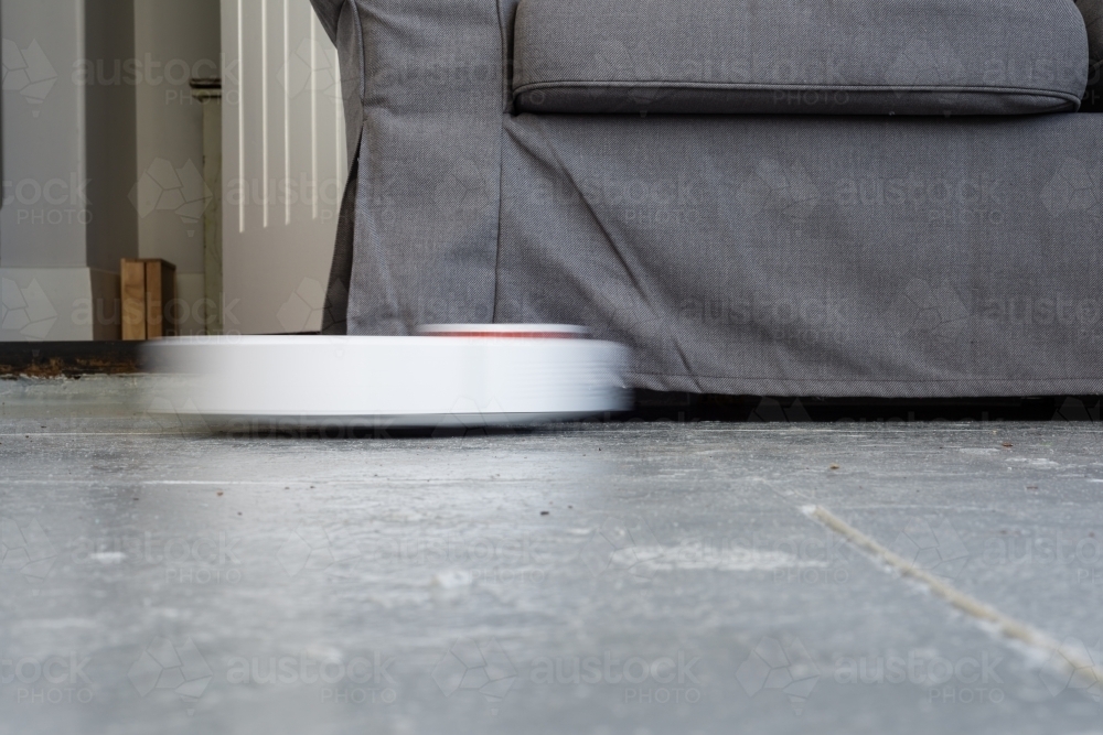 Image of robot vacuum moving around the floor - Austockphoto