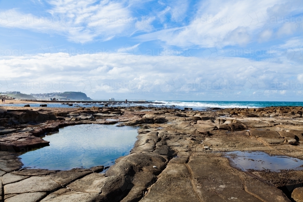 Image of Rock pool reflecting the sky at beach - Austockphoto