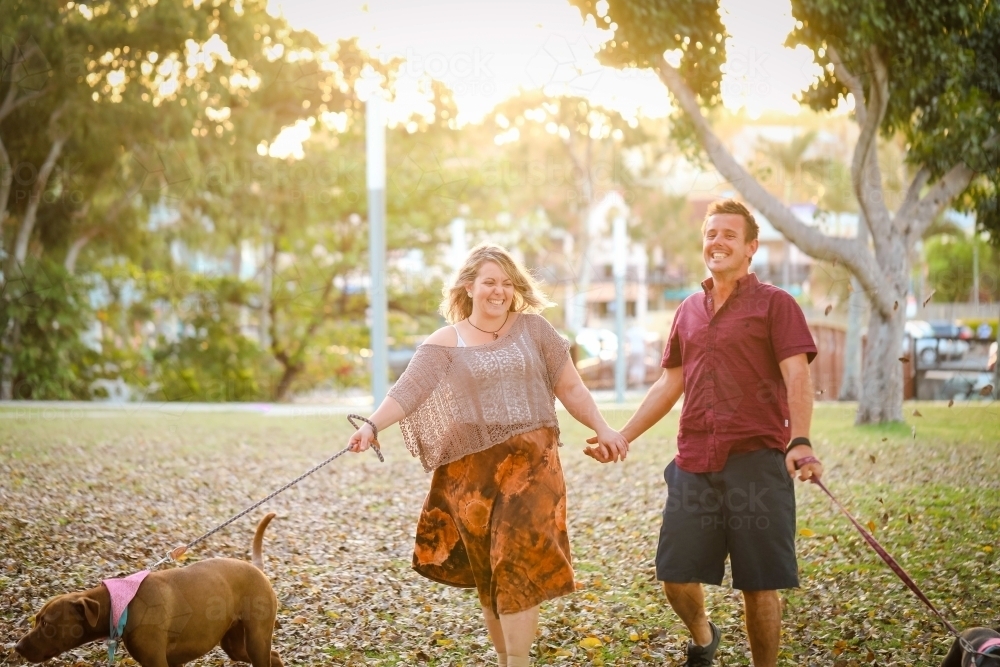 Image of Romantic couple walking dogs in the park in golden afternoon ...