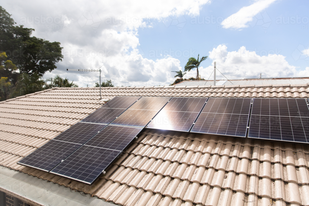 Image of rooftop solar on a suburban house with a tile roof - Austockphoto