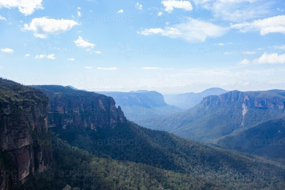 Image of Rugged mountain ranges dip into tree filled valley seen from ...