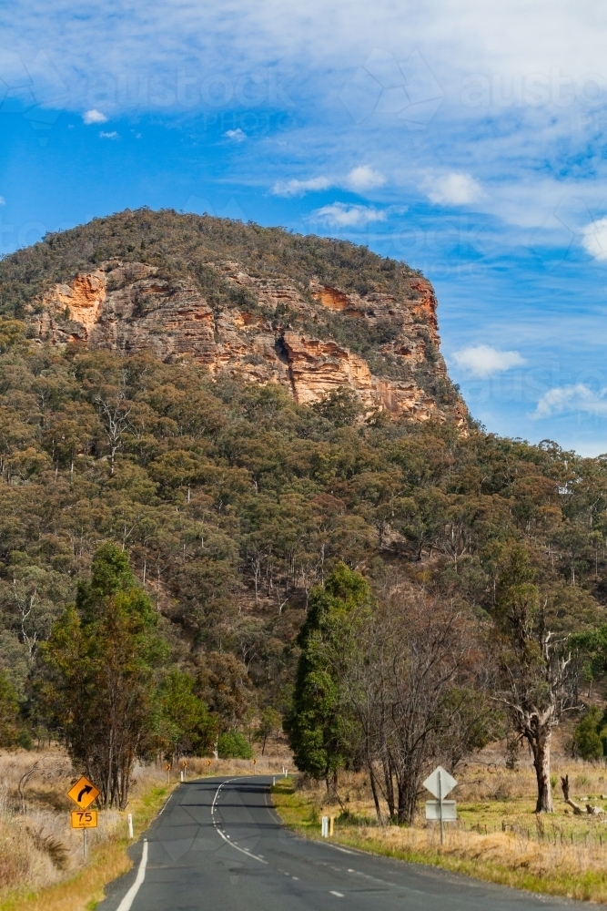 Image of Rural road bending around outcropping cliff in farmland ...