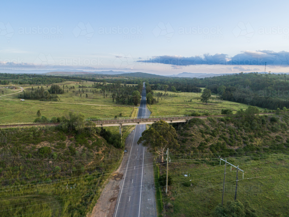 Image of Rural road with train track overpass bridge from aerial view ...