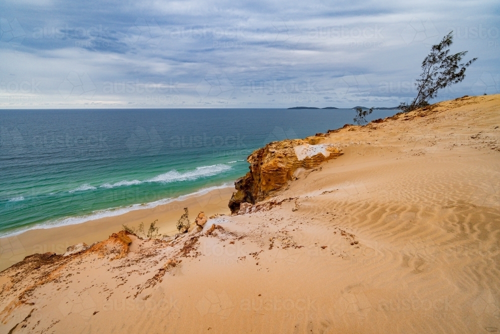 Image of Sand dunes on the edge of a cliff above a blue ocean ...