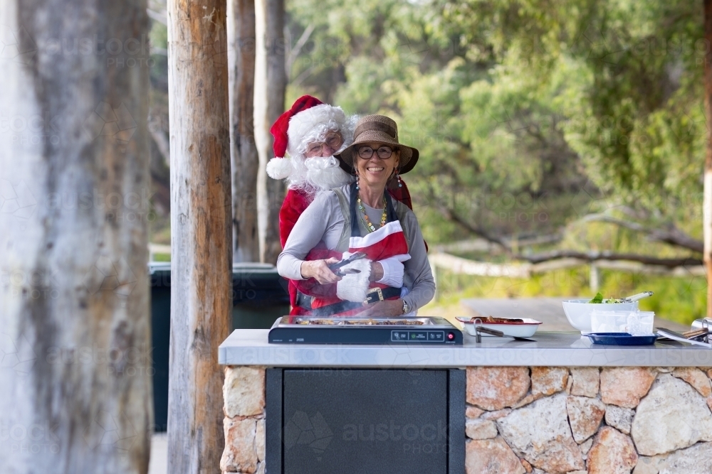 Image of santa and mrs claus cooking a bbq in a park for a christmas ...