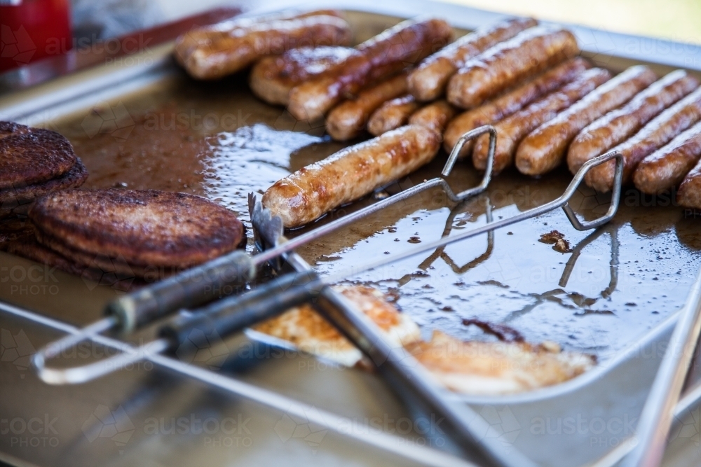 Image of Sausages on a BBQ at a park - Austockphoto