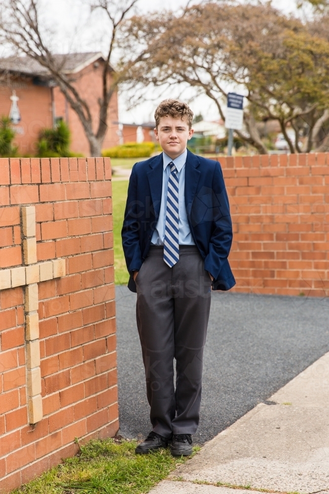 Image of School boy in uniform standing with hands in pockets at ...