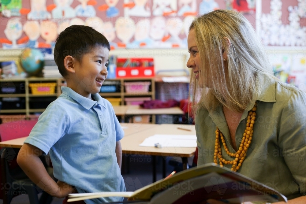 Image of School boy showing his work to the teacher - Austockphoto