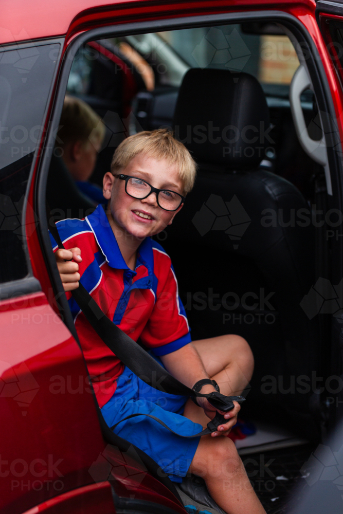 Image of School boy student in car buckling himself in with car seat ...