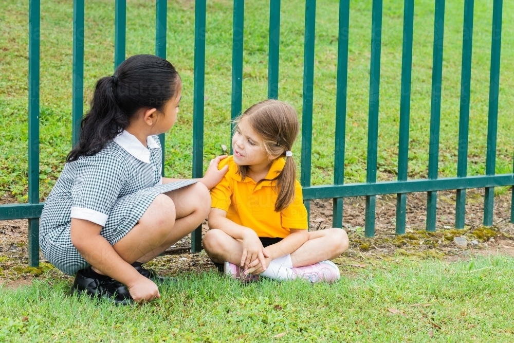 Image of school kid comforting lonely younger girl in playground who ...
