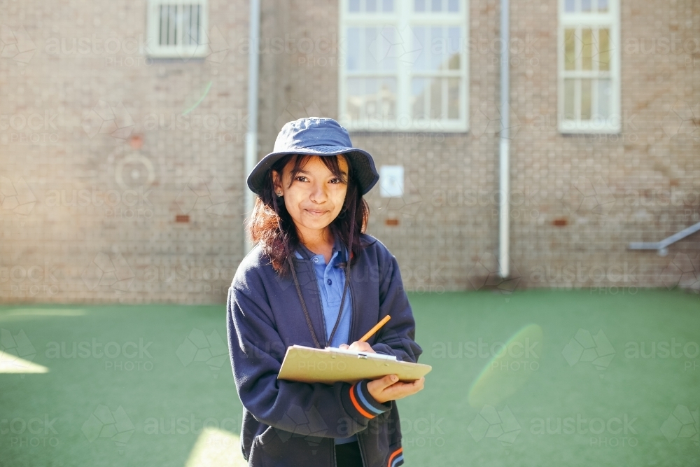 Image of School student standing holding a clipboard outside the ...