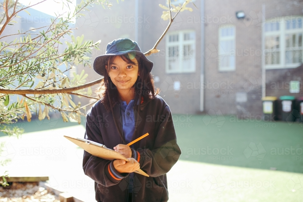 Image of School student standing holding a clipboard outside the ...