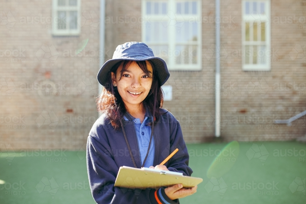 Image of School student standing holding a clipboard outside the ...