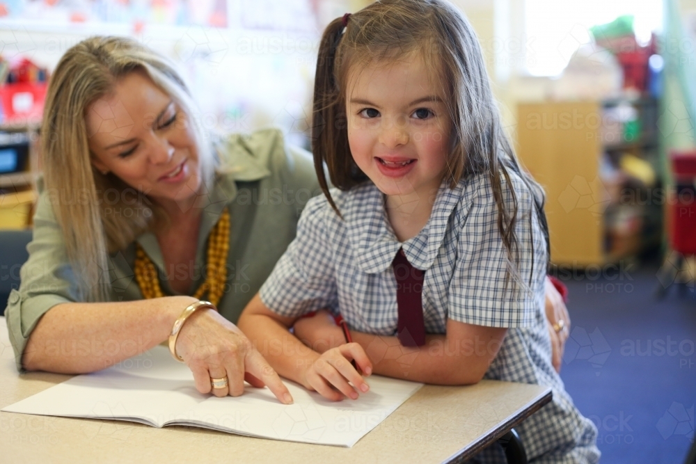 Image of School teacher helping child with her work - Austockphoto