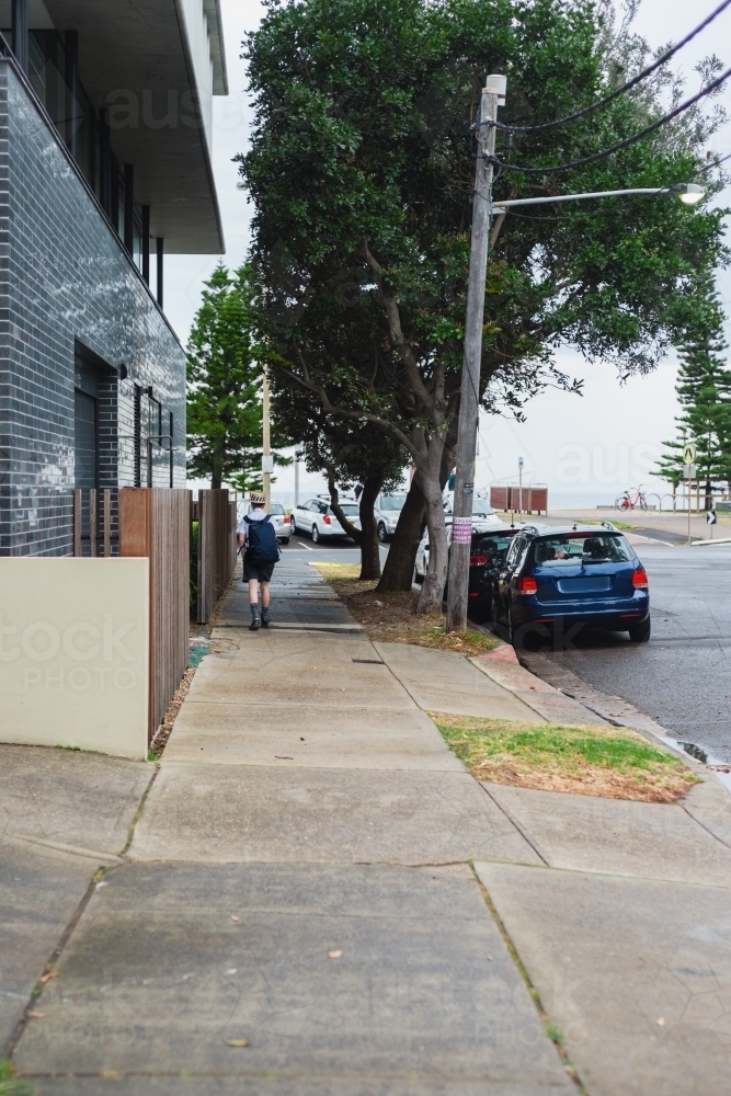 Image of schoolboy walking to the bus stop - Austockphoto