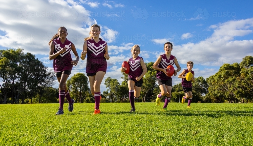 Image of schoolchildren running towards camera in football uniforms on ...