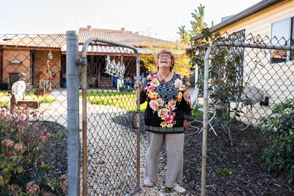 Image of Senior Australian woman walking out gate down garden path in ...