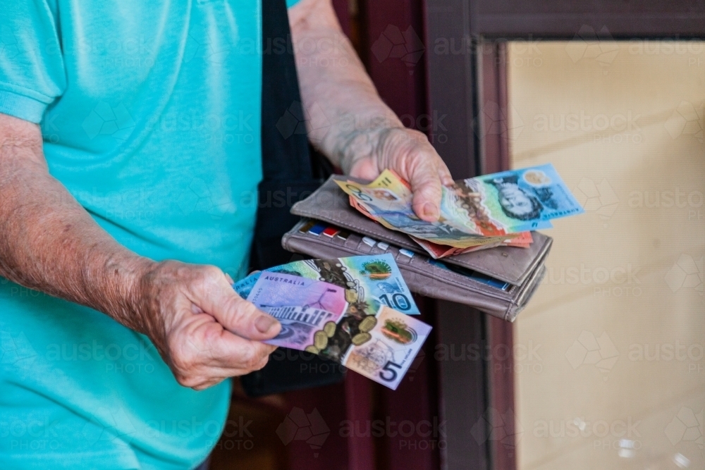 Image of Senior citizen handing over cash at home front door - Austockphoto