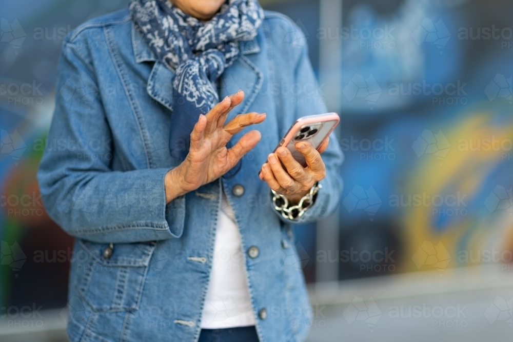 Image of senior lady holding smartphone and tapping screen - Austockphoto