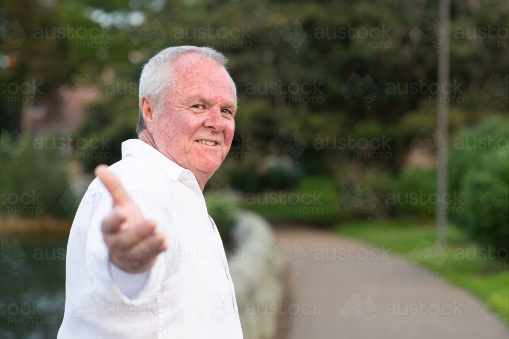 Image of senior man stretching his hand back - Austockphoto