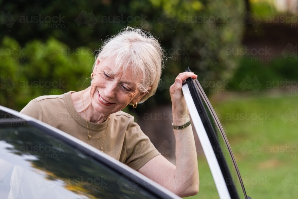 Image of senior woman geting into a car - Austockphoto