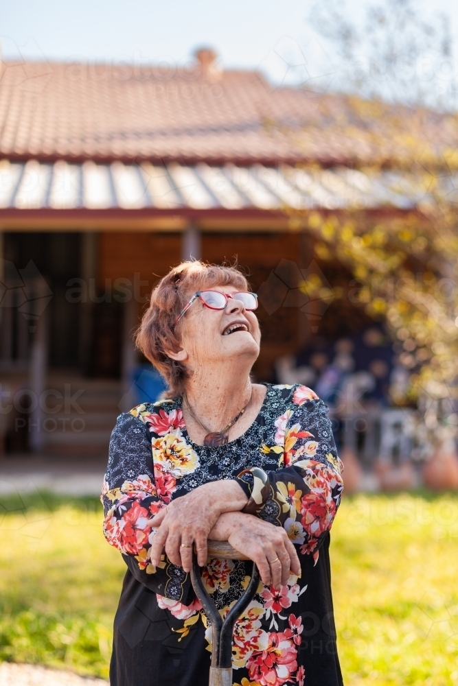 Image of Senior woman watching birds in the sky while leaning on shovel ...