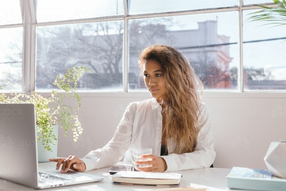 Image of Serious girl working intently on her laptop - Austockphoto