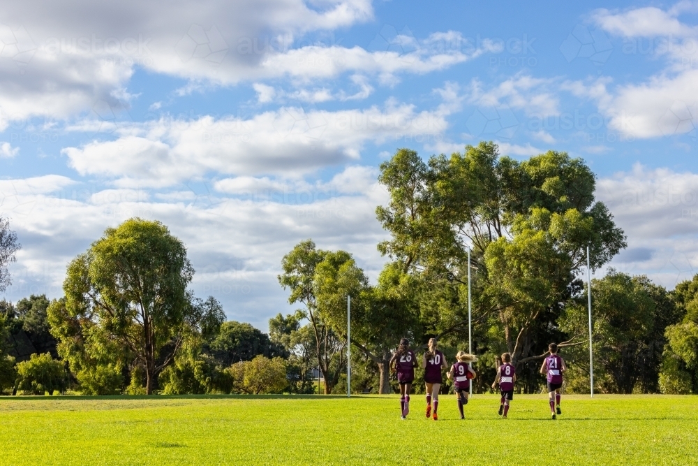 Image of several kids in footy uniforms running towards goalposts on ...