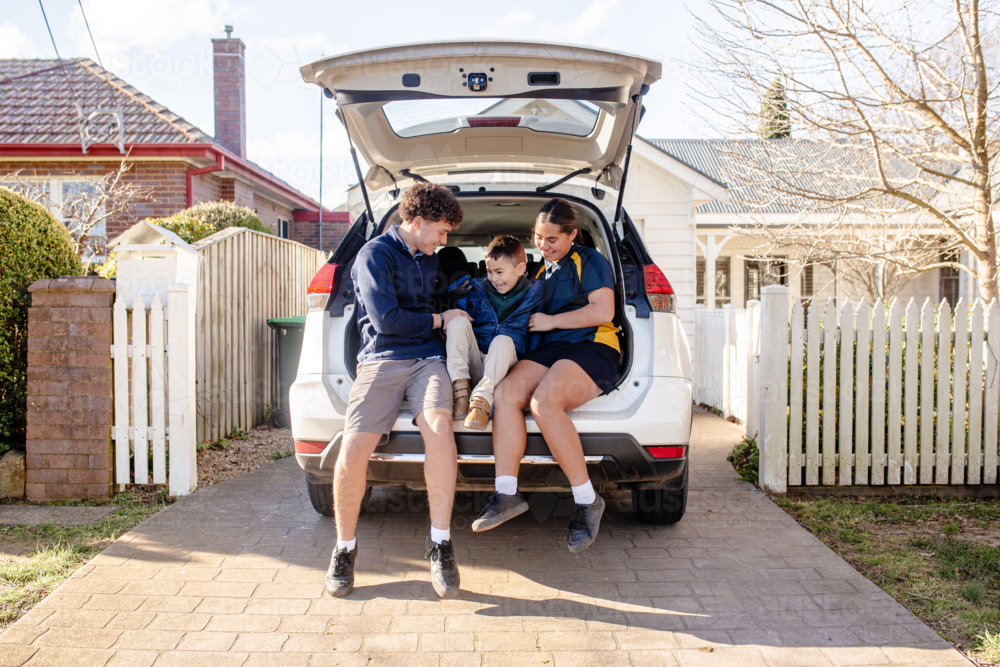 Image of Siblings having fun while seated in the car boot - Austockphoto