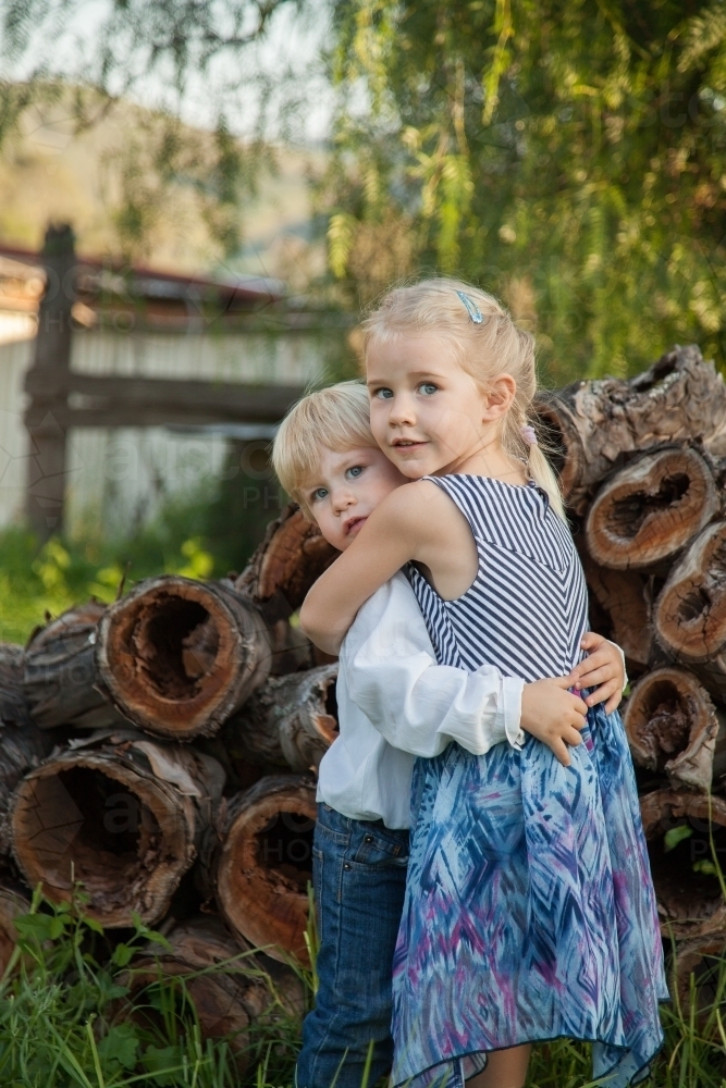 Image of Siblings hug one another outside - Austockphoto