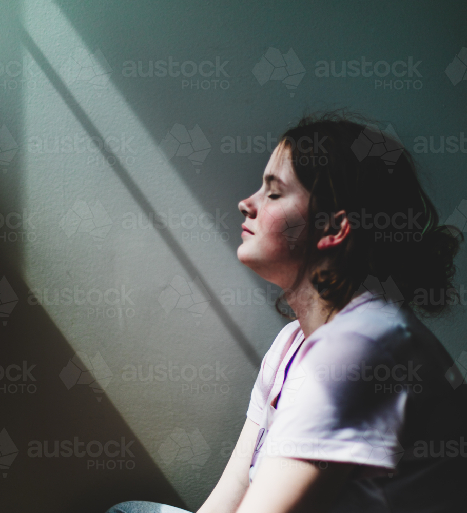 Image of Side profile of a young woman sitting thinking as he sun light ...