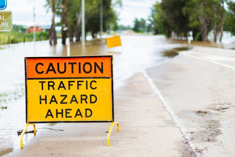 Image of Sign with floodwaters over road - caution traffic hazard ahead ...