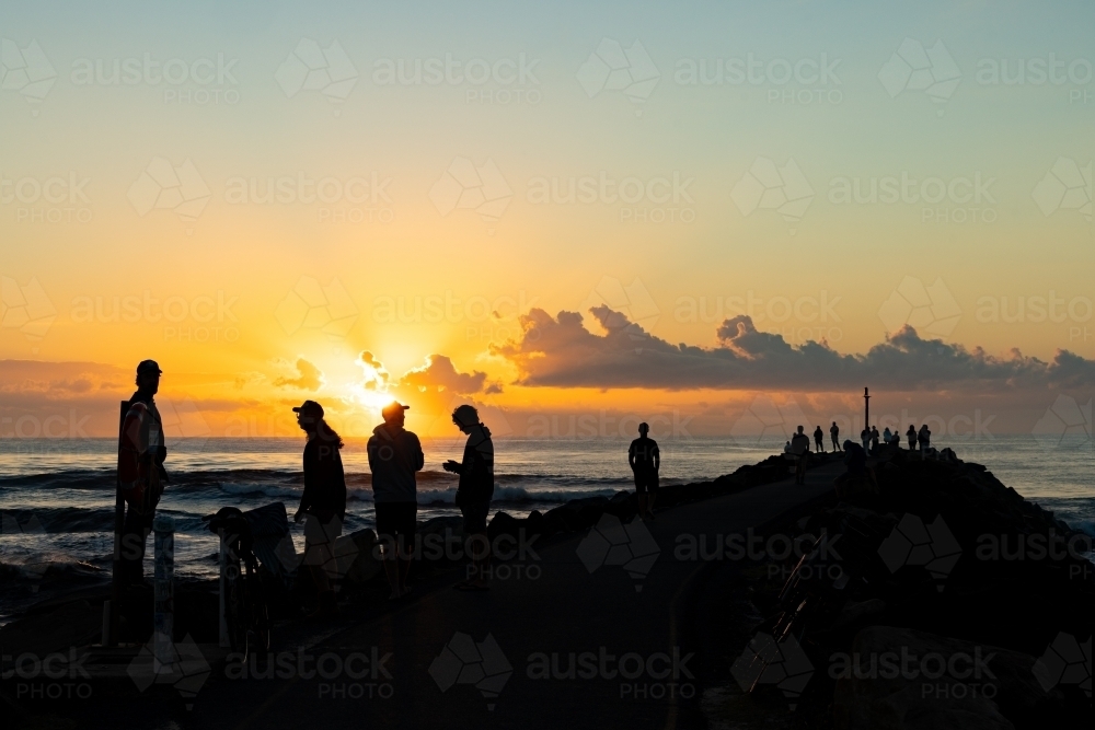 Image of Silhouette of group of people gathering to watch the sunrise from the breakwall at ...