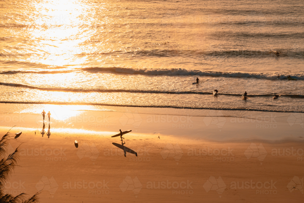 Image of Silhouettes and shadows of early morning surfers at first ...