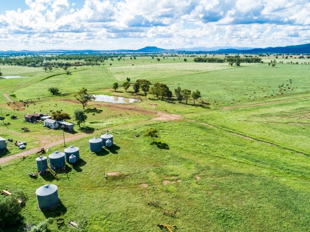 Image of Silos and dam in green paddocks of grass on a farm - Austockphoto