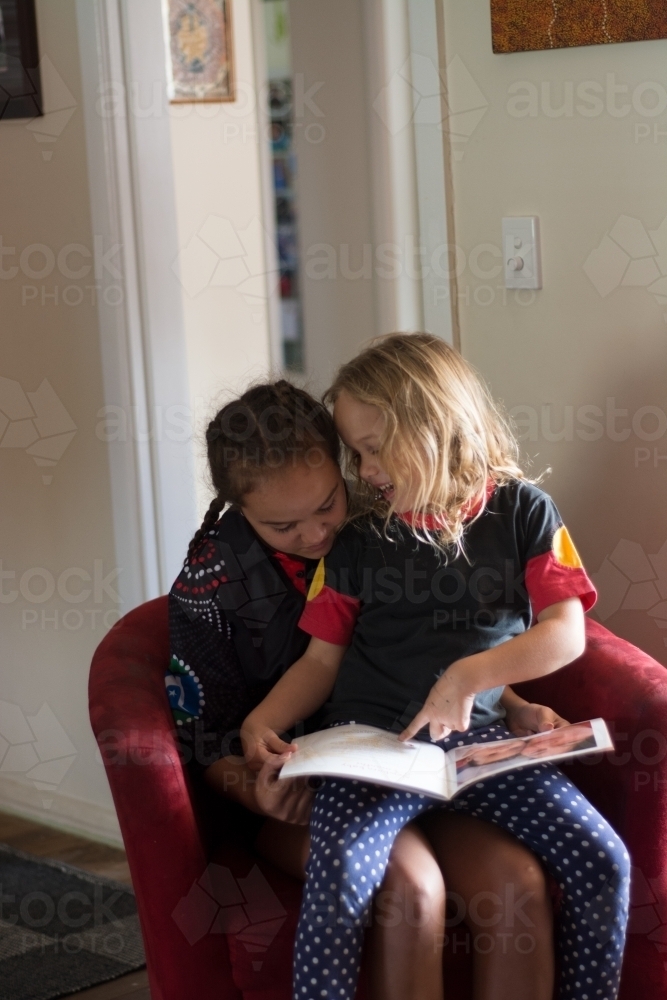 Image of Sisters reading together - Austockphoto