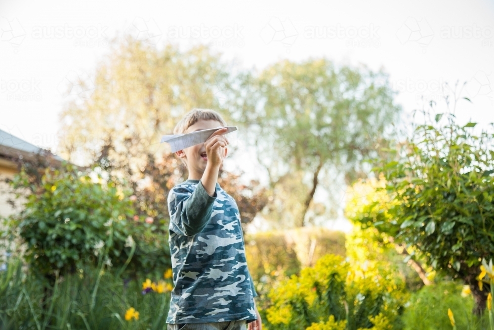 Image of Six year old boy flying paper planes in the garden - Austockphoto