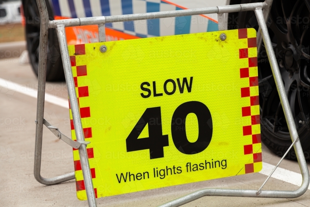 Image of Slow 40 when lights flashing sign beside police car - Austockphoto