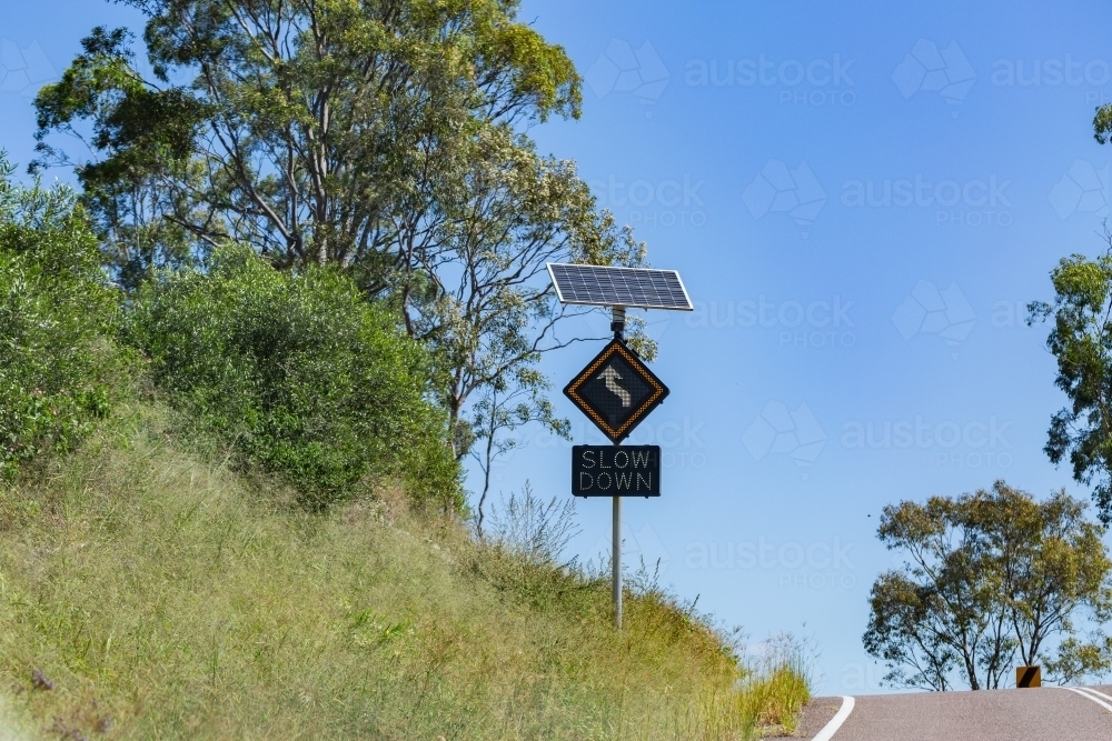 Image of Slow down digital sign powered with solar beside road crest ...