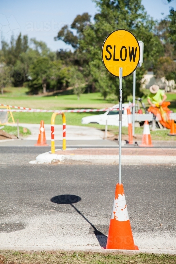 Image of Slow road work lollipop sign in road cone - Austockphoto