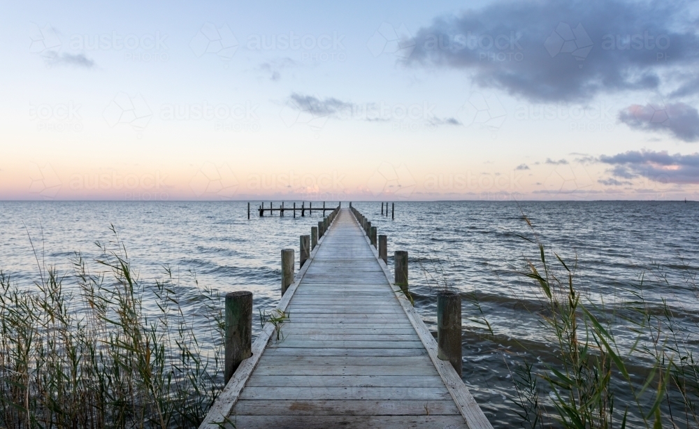 Image of small jetty on lake at sunset - Austockphoto
