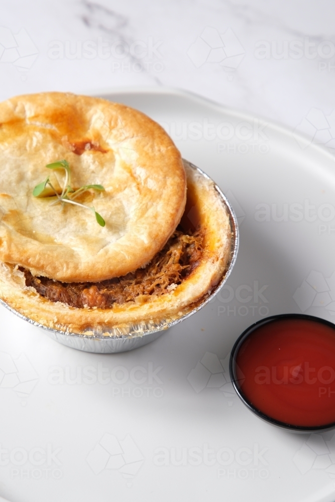 Image of Small open meat pie with side of tomato sauce - Austockphoto