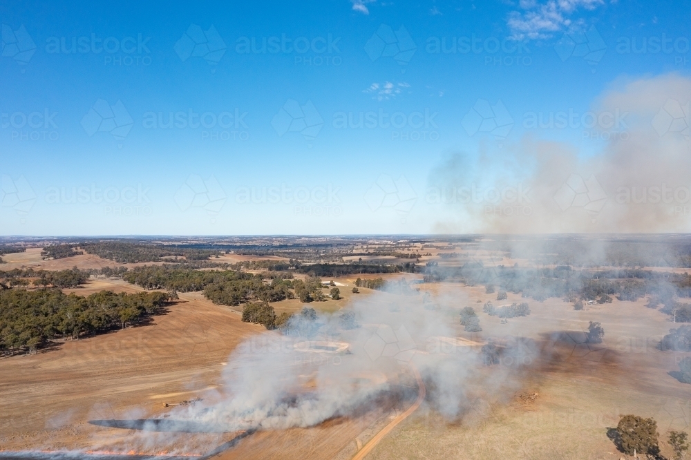 Image of Small paddock fire with smoke drifting across dry landscape ...